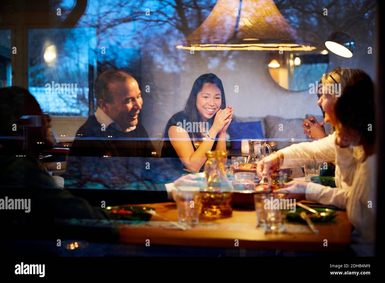 Multi-generation family enjoying dinner at table seen through glass ...