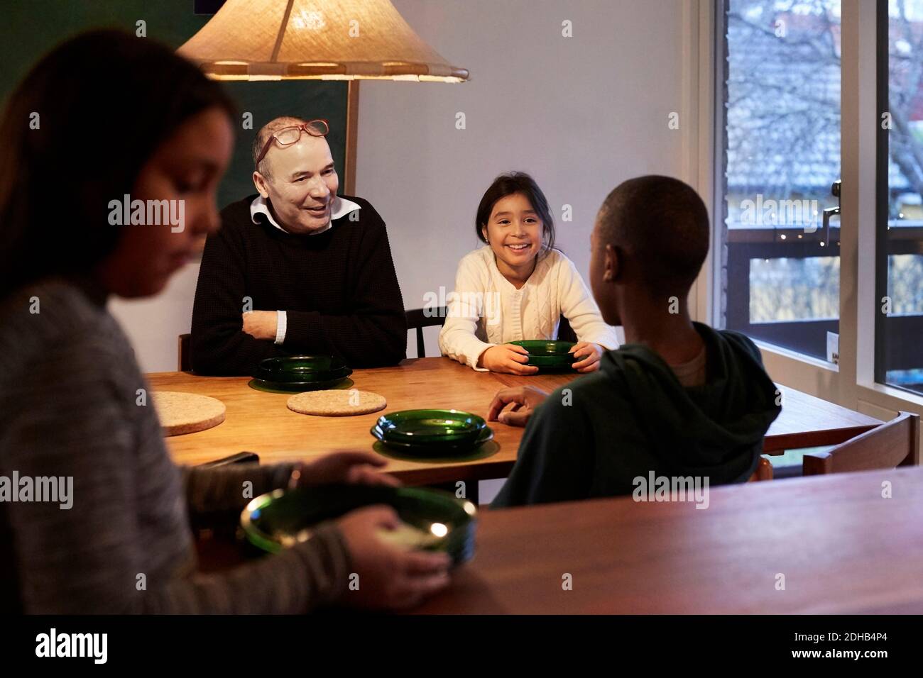 Happy family talking while sitting at illuminated table Stock Photo - Alamy