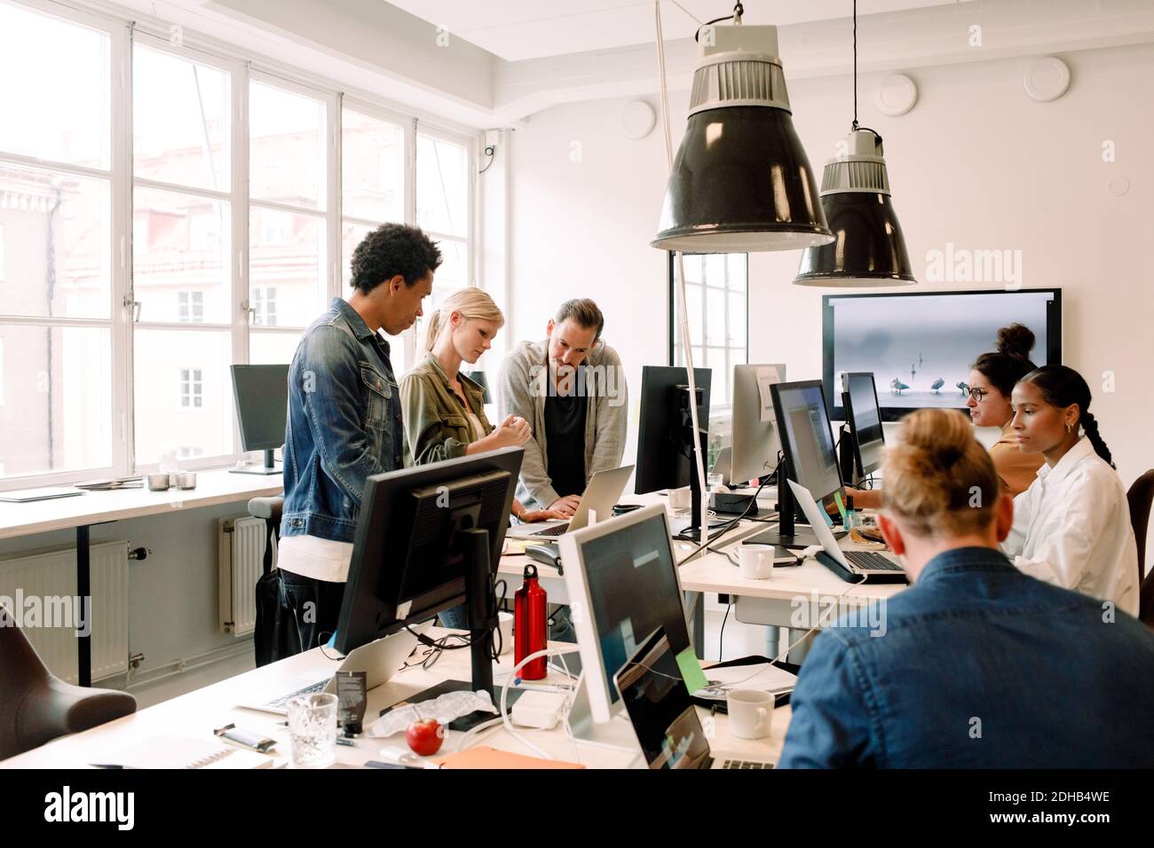 Creative business people working on computers in open plan office Stock ...