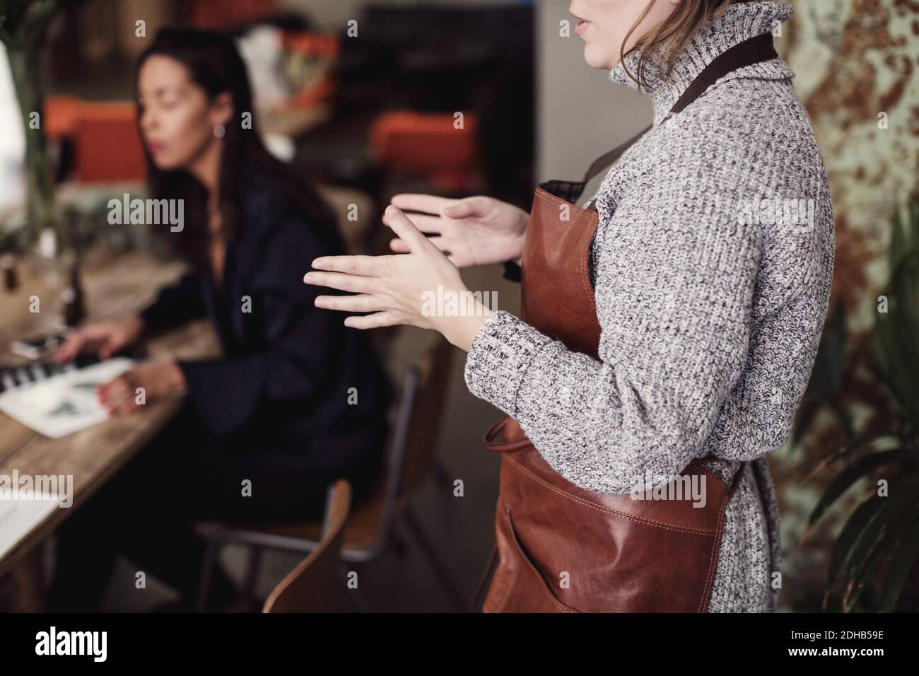 Midsection of female owner gesturing while standing at workshop Stock ...