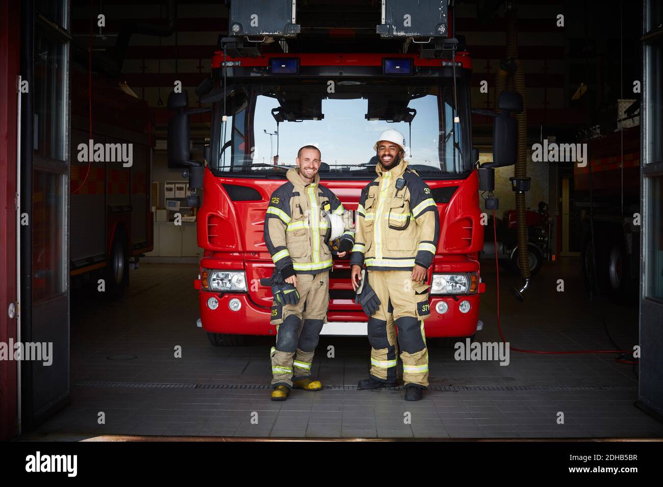 Portrait of firefighters standing in front of fire engine at fire ...