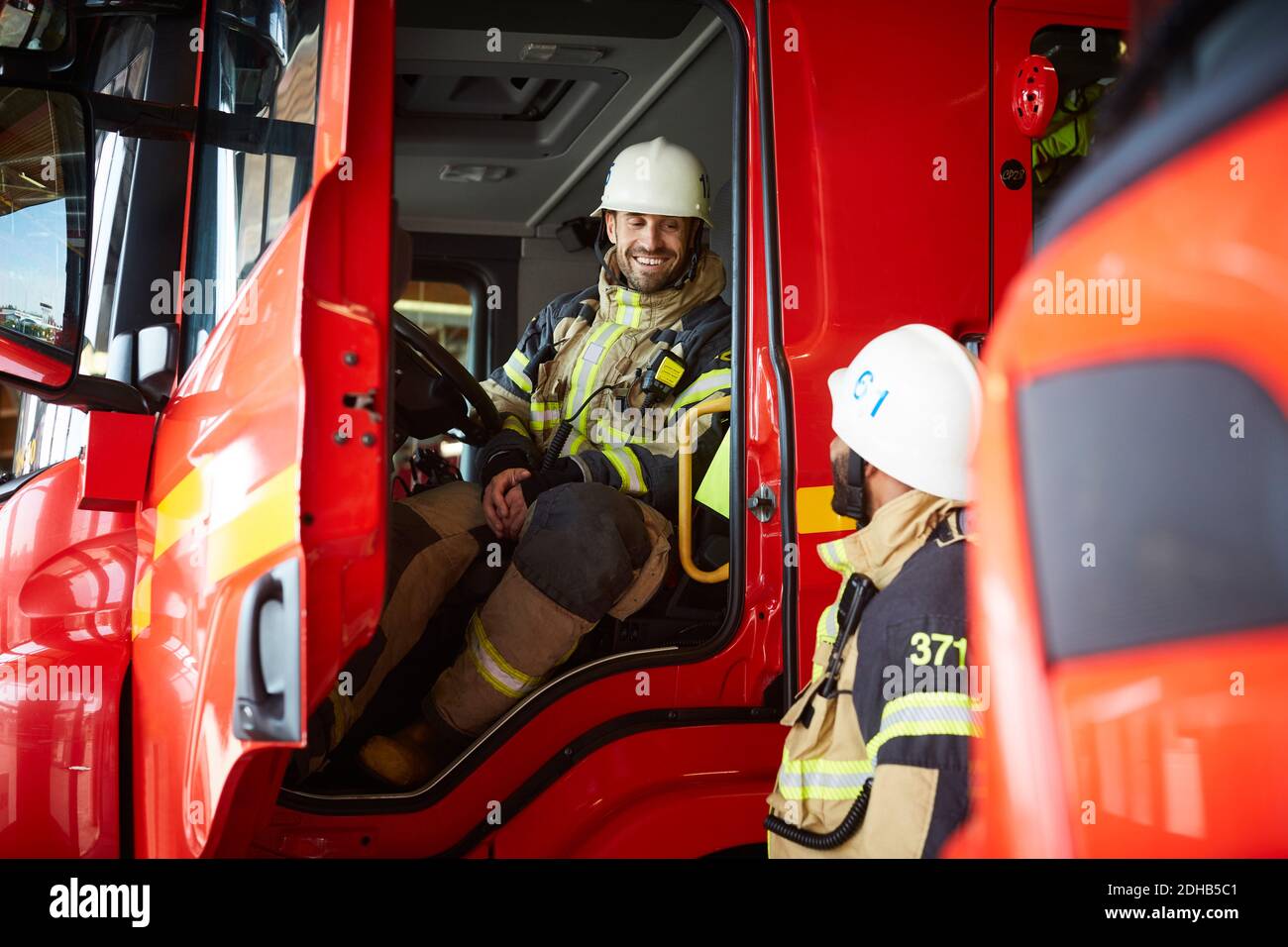Firefighter talking with coworker while sitting in fire truck at fire ...