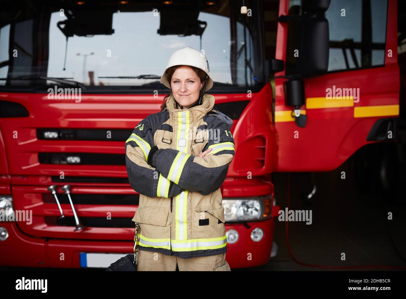 Portrait of confident female firefighter standing with arms crossed ...