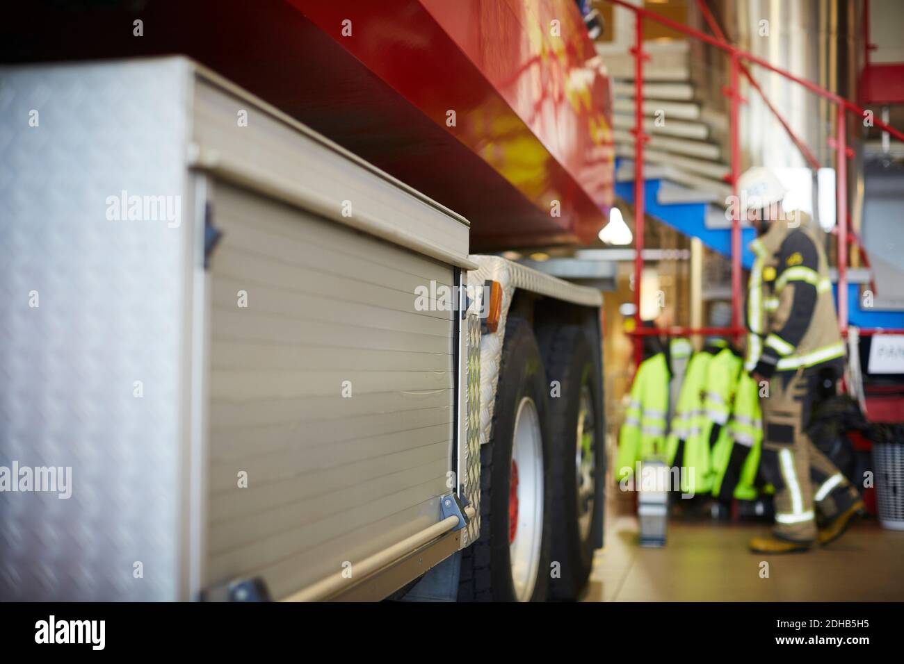 Cropped image of fire engine with worker in background at fire station ...