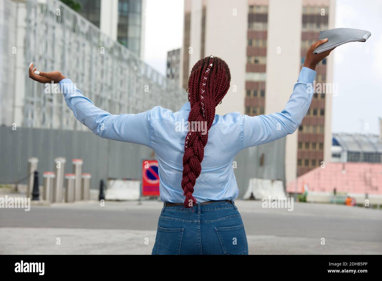 Happy businesswoman standing back with long red braids, holding a ...