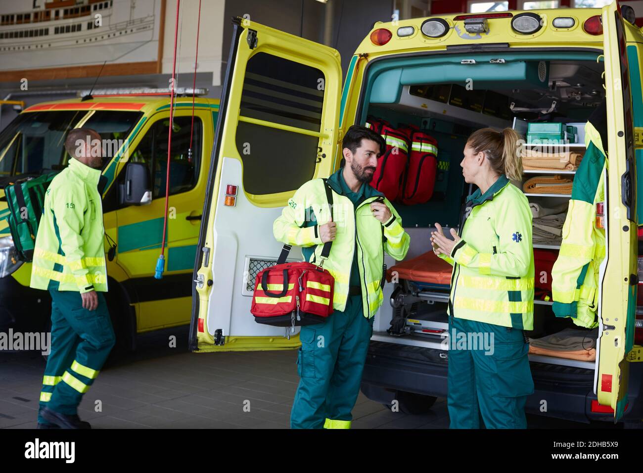 Male paramedic talking to female coworker while standing by ambulance ...