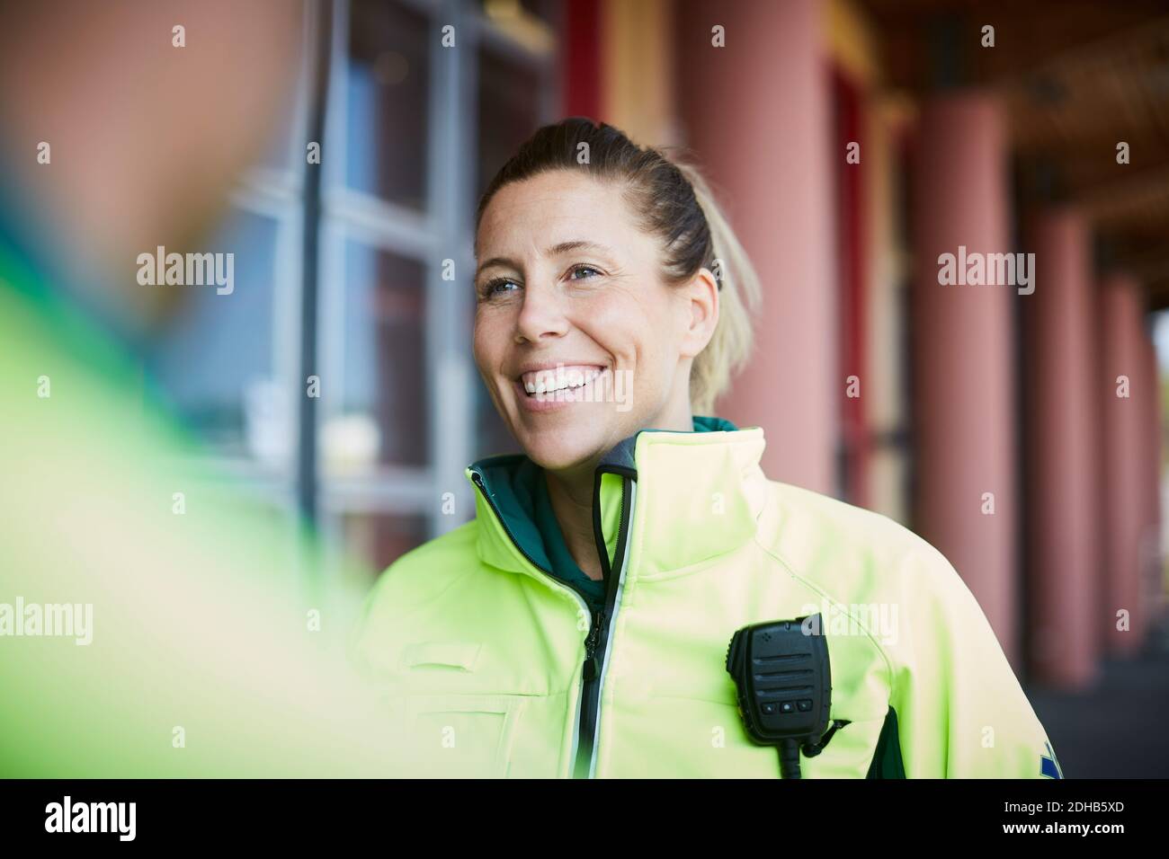 Smiling female paramedic looking away standing outside hospital Stock ...