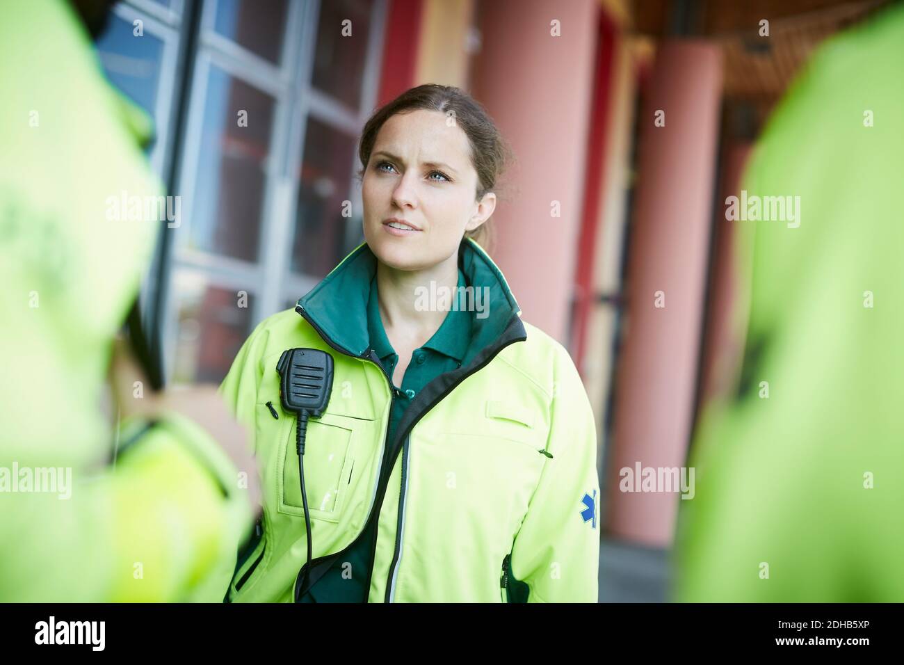 Female mid adult paramedic looking away while standing outside hospital ...