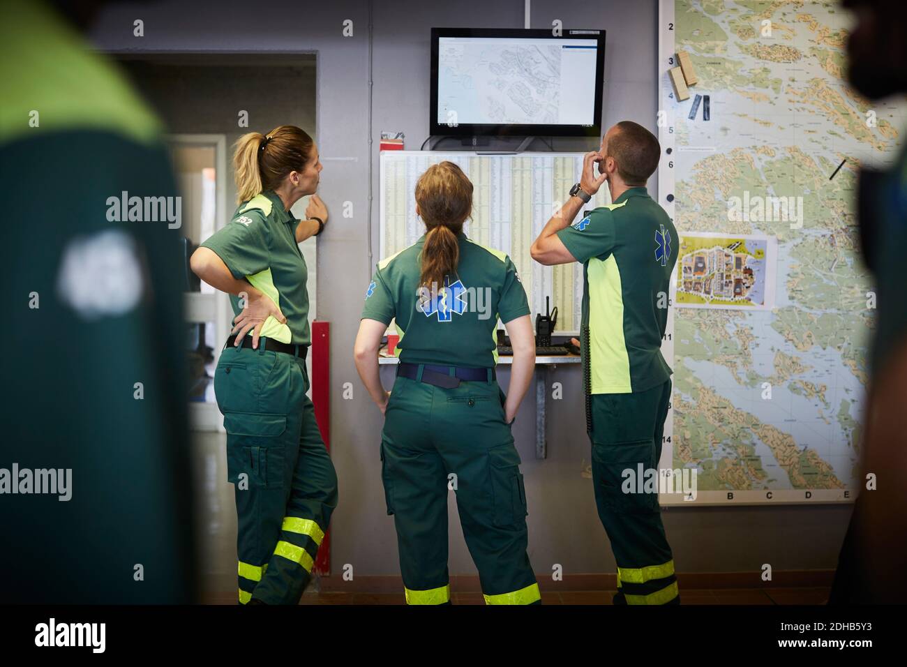 Male and female paramedics discussing while looking at screen in ...