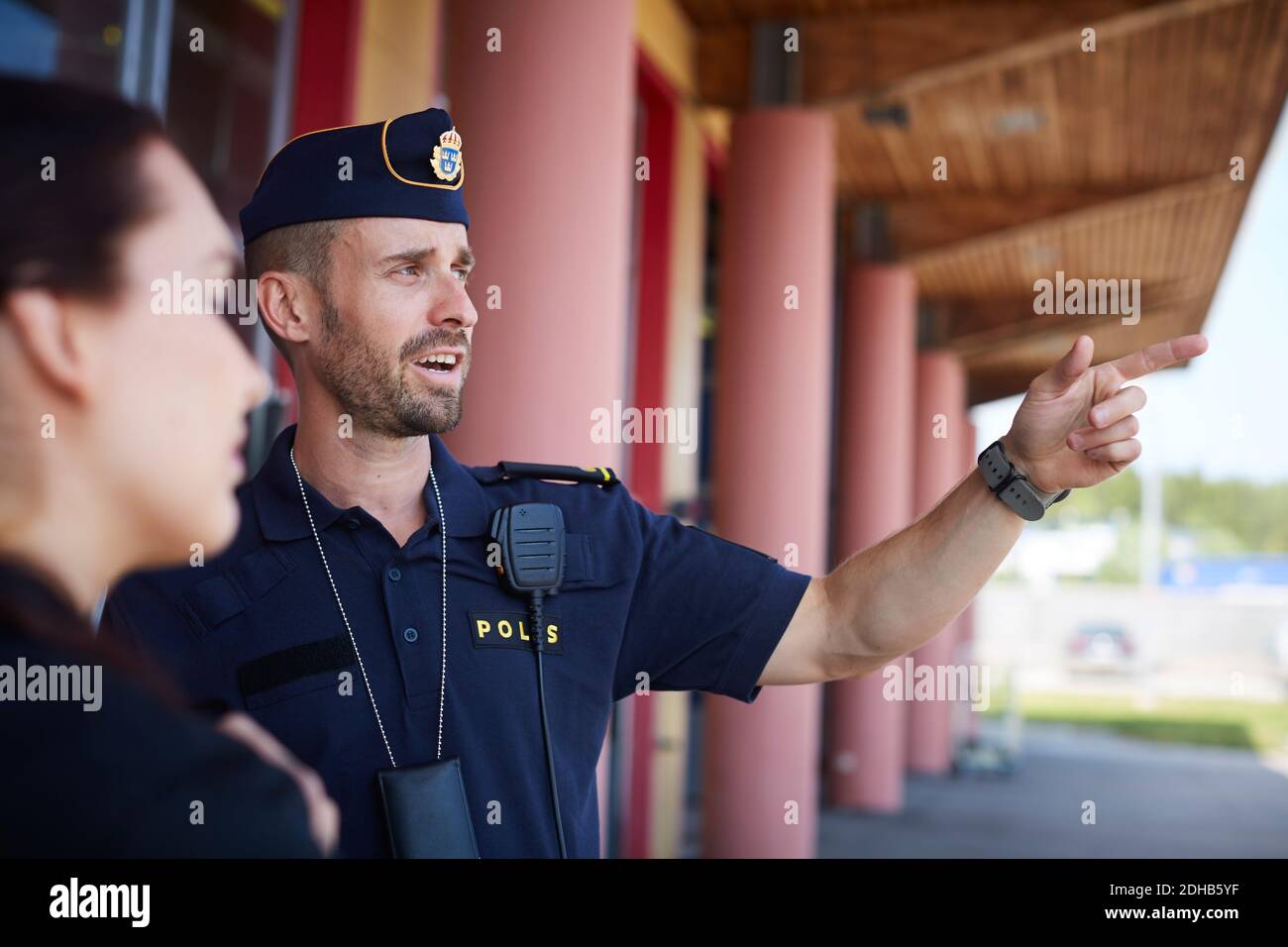 Male police officer pointing while directing coworker outside police ...