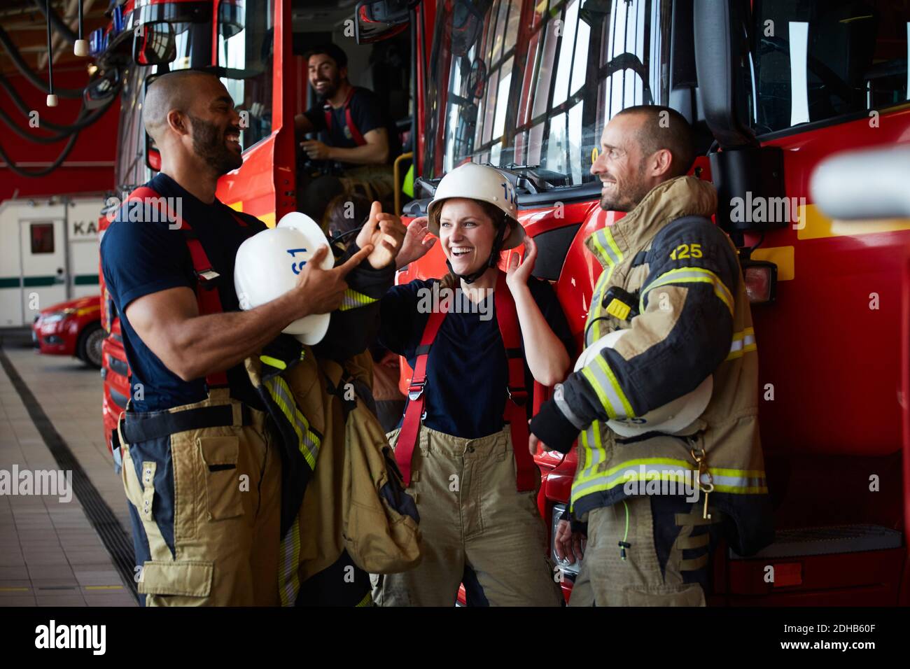 Happy firefighters discussing while standing by fire truck in fire ...