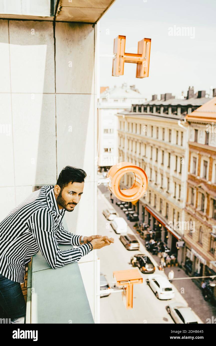 Side view of man leaning on hotel balcony during sunny day Stock Photo ...