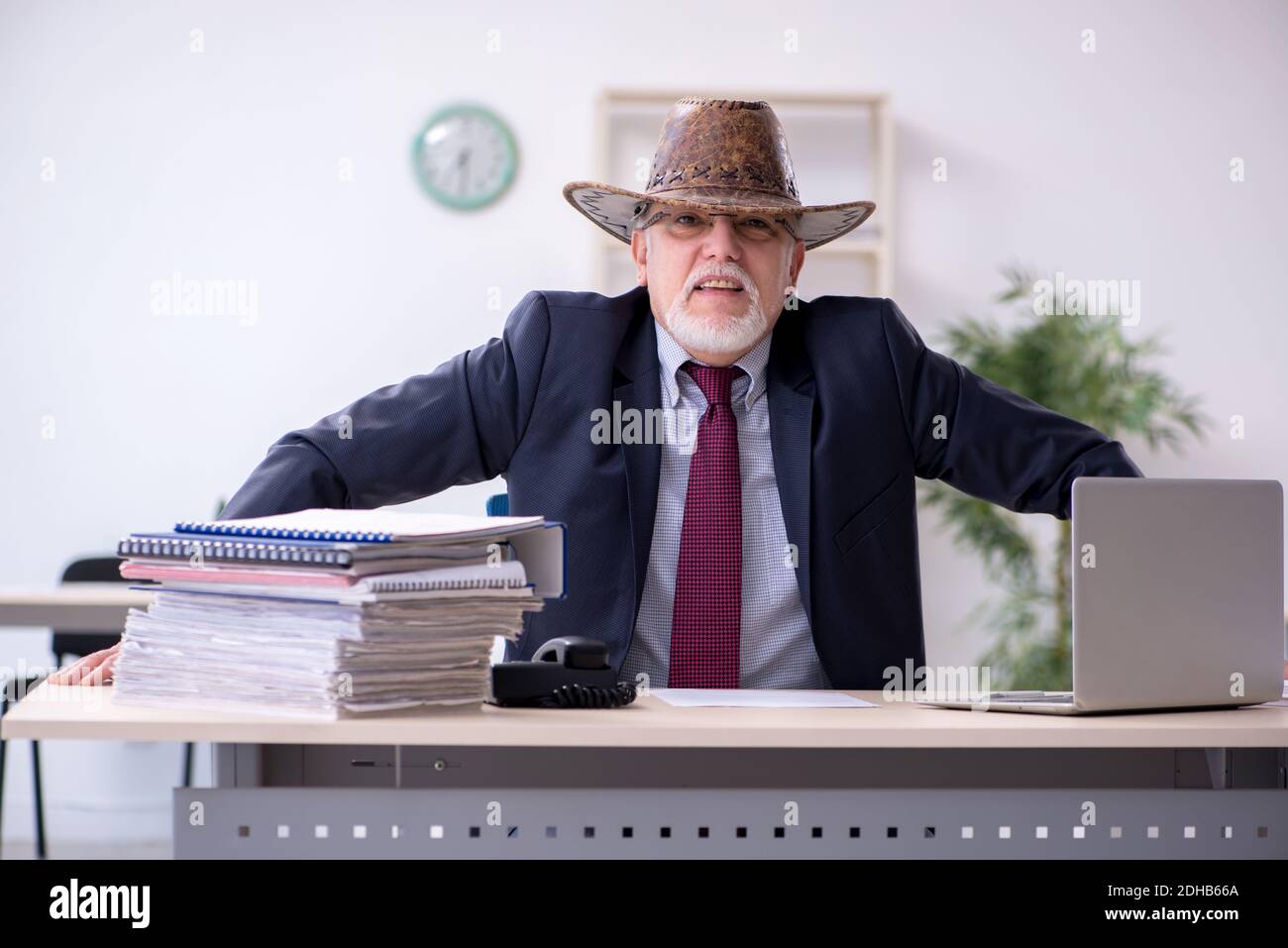 Funny old boss in cowboy hat in the office Stock Photo - Alamy