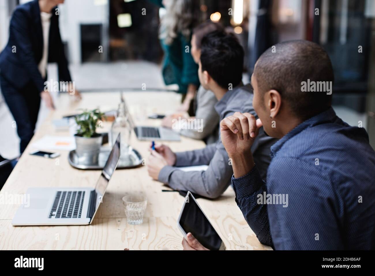 Business colleagues listening while sitting at table during meeting ...