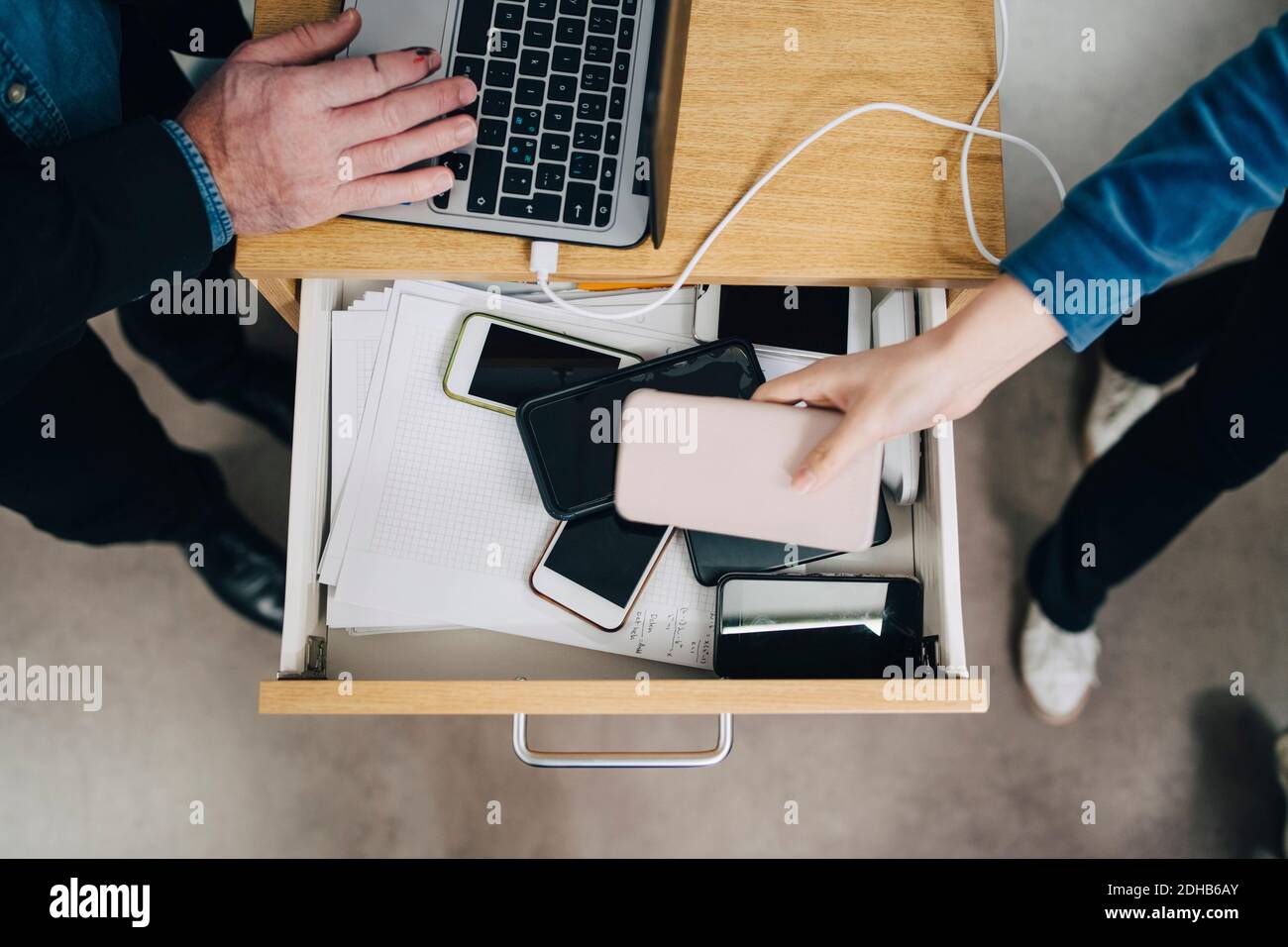 High angle view of female student collecting phone in drawer during ...