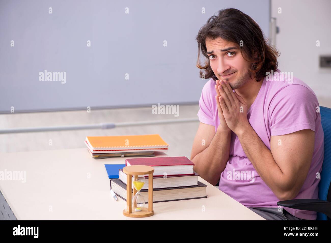 Young male student in the classroom at time management concept Stock ...