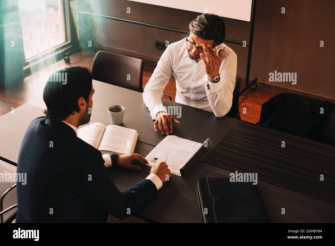 High angle view of male lawyer showing file to mature stressed client ...