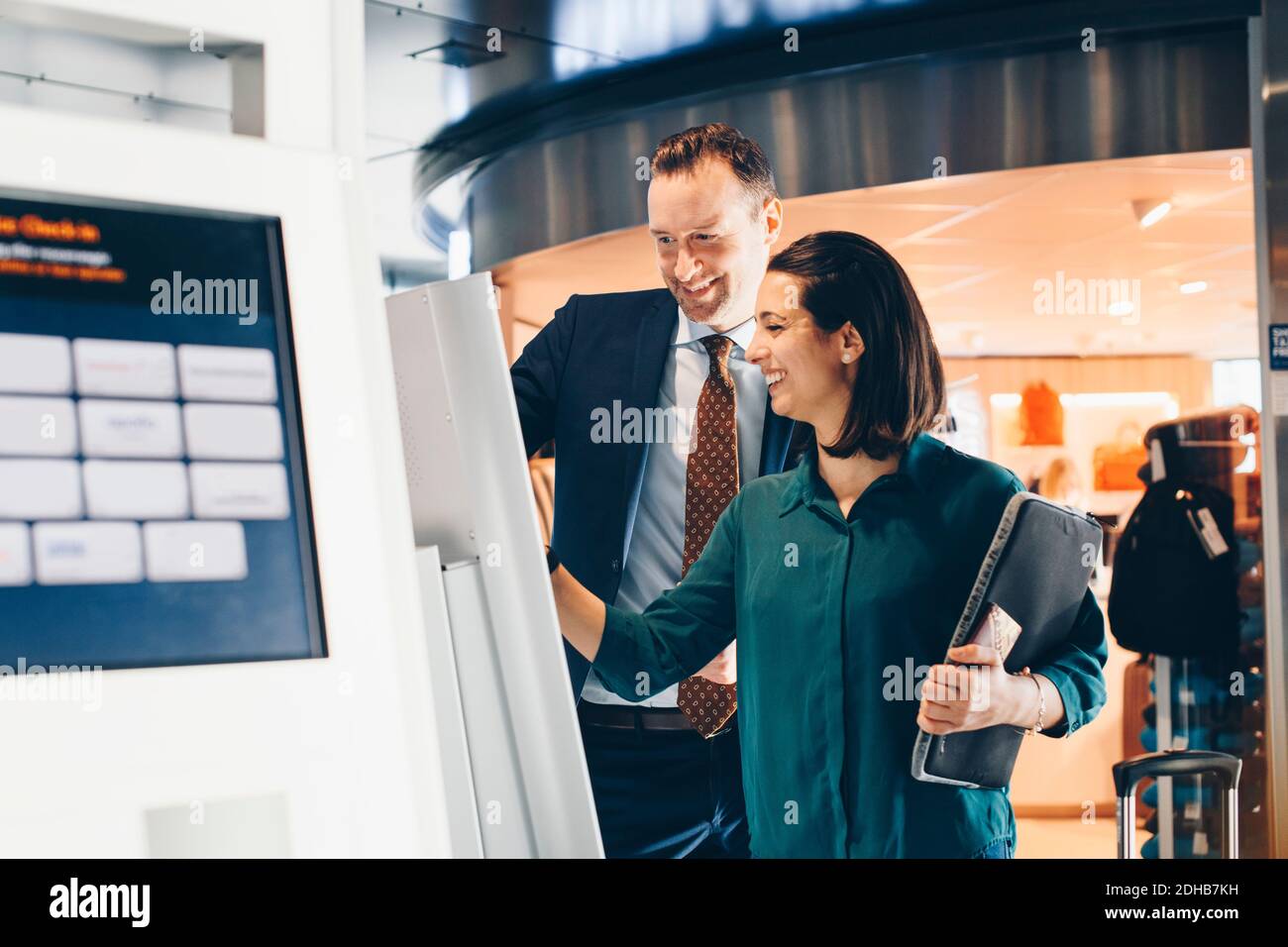 Happy business couple using self-service check-in machine at airport ...