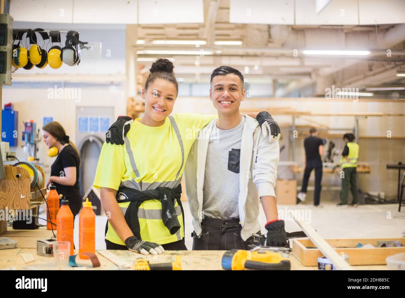 Portrait of smiling female trainee standing with arm around male ...