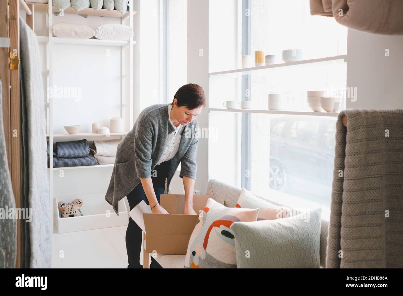 Mature female craftsperson unpacking products from cardboard box in ...
