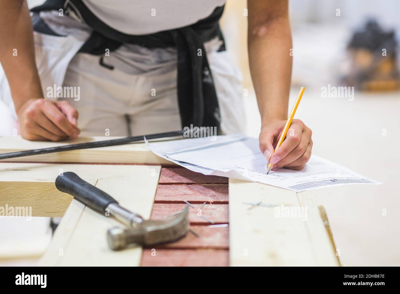 Midsection of young female trainee drawing on paper at workbench in ...