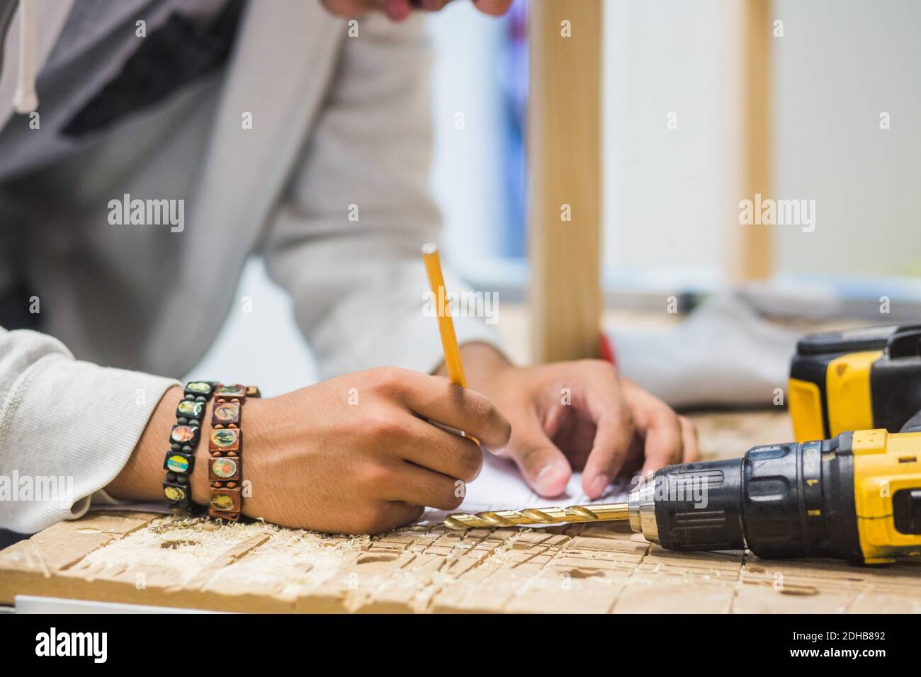 Midsection of male teenage trainee drawing diagram on paper at ...