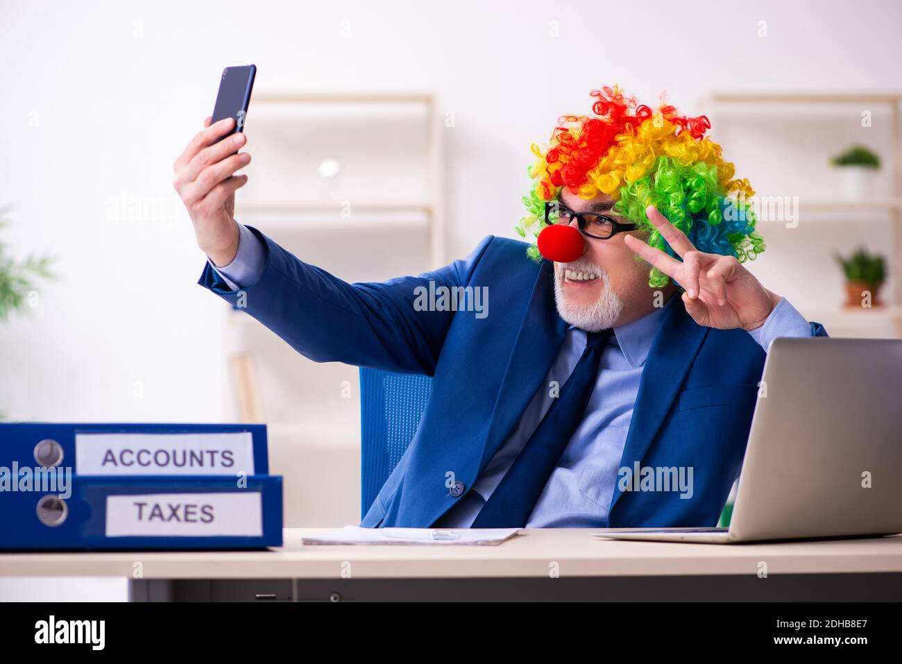 Old businessman clown working in the office Stock Photo - Alamy