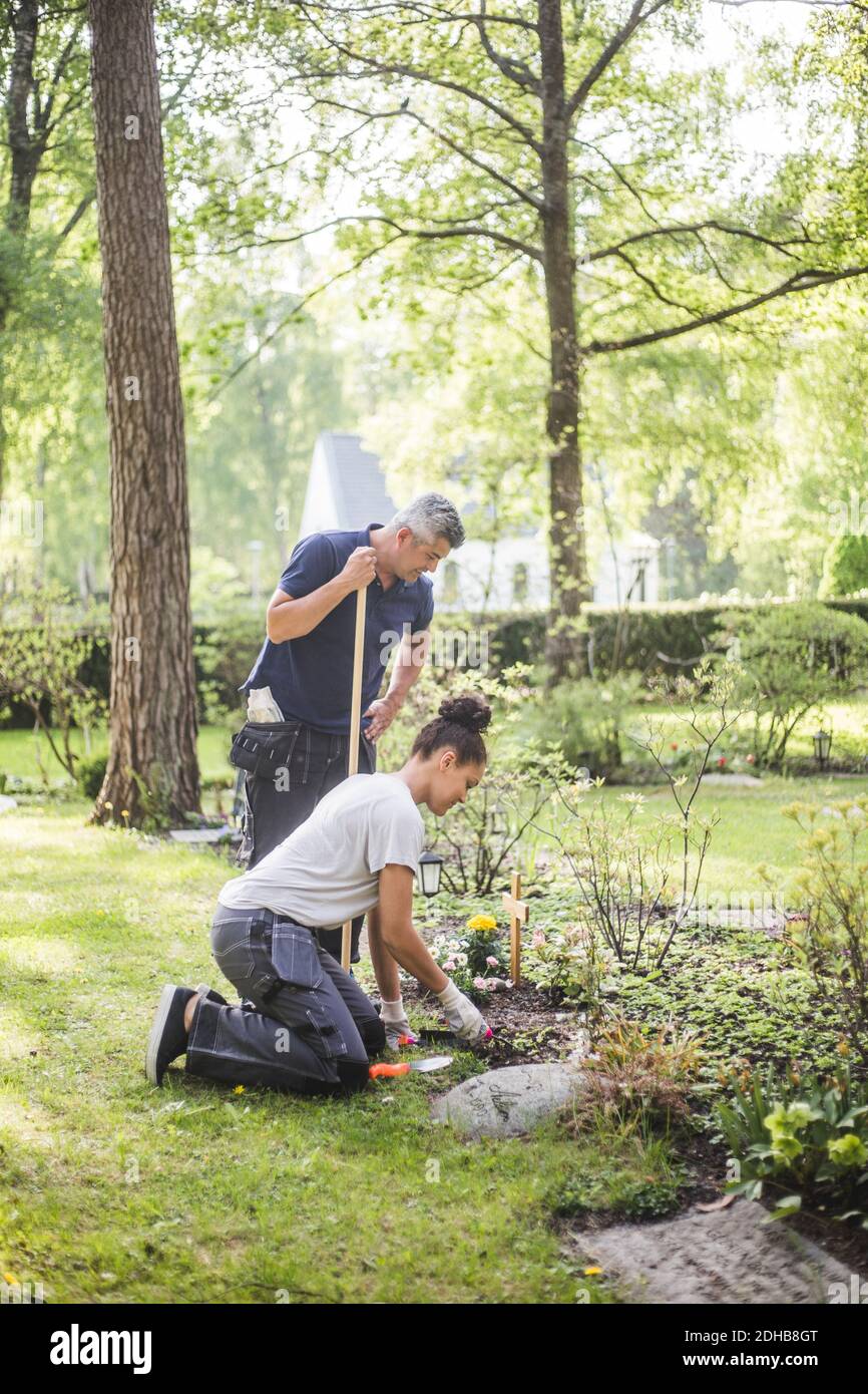 Full length of instructor watching young female trainee planting at ...