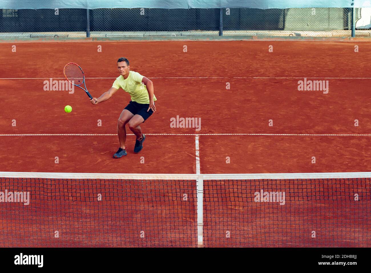 Young handsome man playing tennis on the tennis court Stock Photo - Alamy