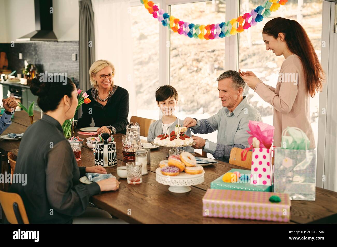 Multi-generation family enjoying birthday cake at table during party ...