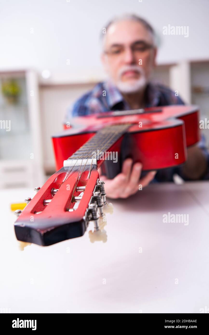 Senior male repairman repairing musical instruments at home Stock Photo ...