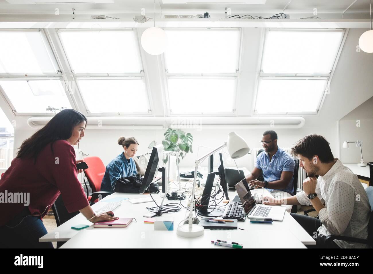 Male and female professionals using computers on desk in creative ...