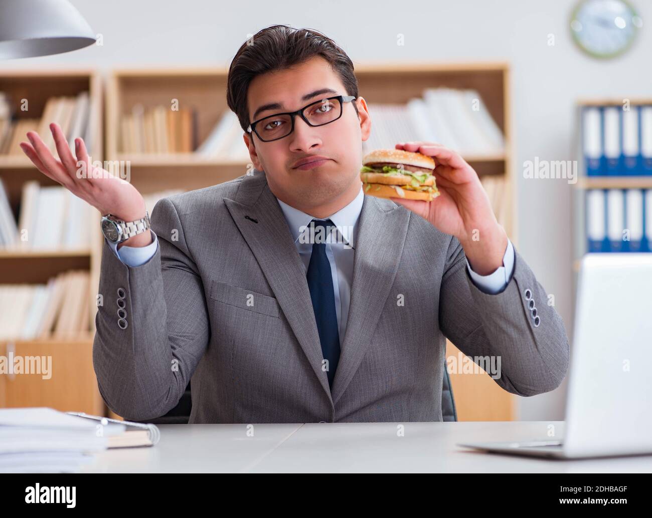 Hungry funny businessman eating junk food sandwich Stock Photo - Alamy