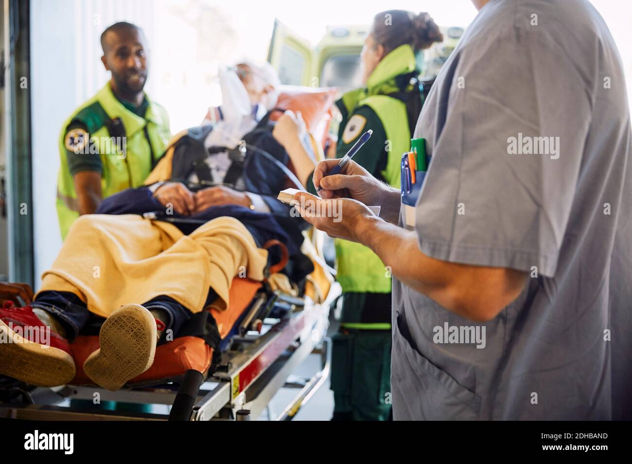 Midsection of male professional writing record against paramedics and ...