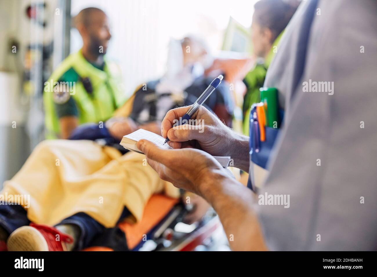 Close-up midsection of male nurse writing medical report against ...