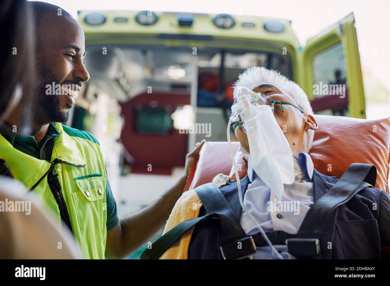 Smiling male paramedic encouraging businessman against ambulance Stock ...