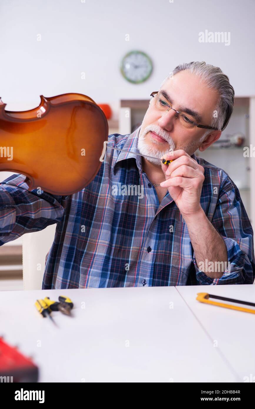 Senior male repairman repairing musical instruments at home Stock Photo ...