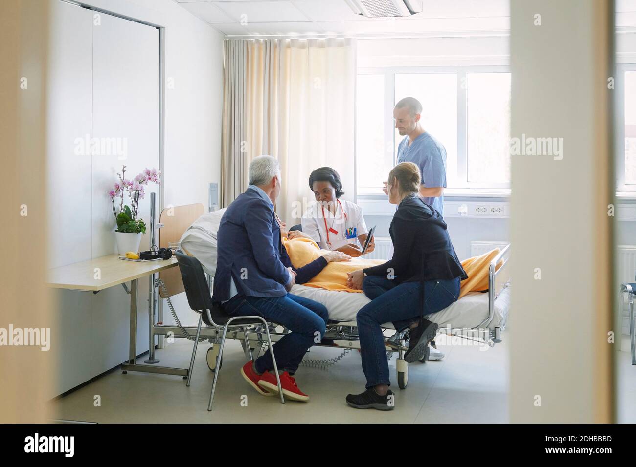 Medical professionals discussing with patient and her friends in ward ...