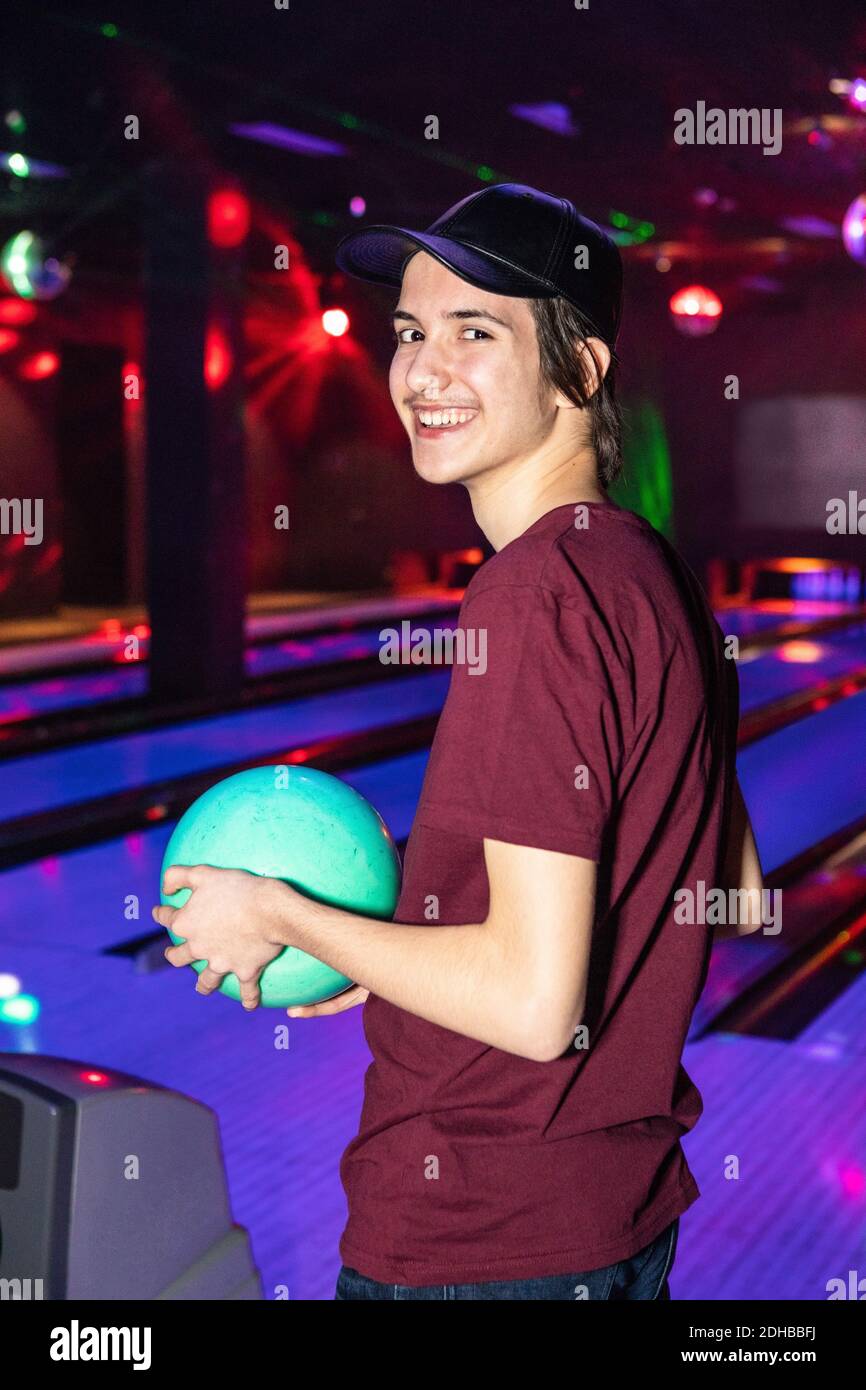 Portrait of smiling teenage boy holding ball at bowling alley Stock ...