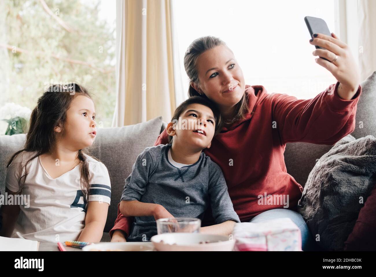 Daughter looking at mother taking selfie with autistic brother while ...