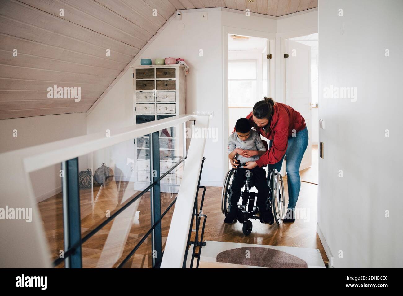 Mother fastening wheelchair buckle for disabled son at home Stock Photo ...