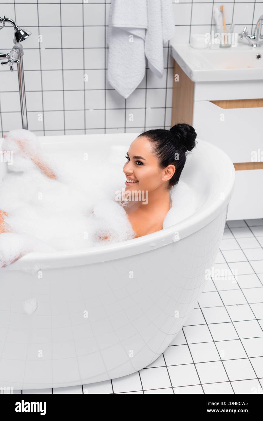 Young cheerful woman bathing with foam in bathtub Stock Photo - Alamy