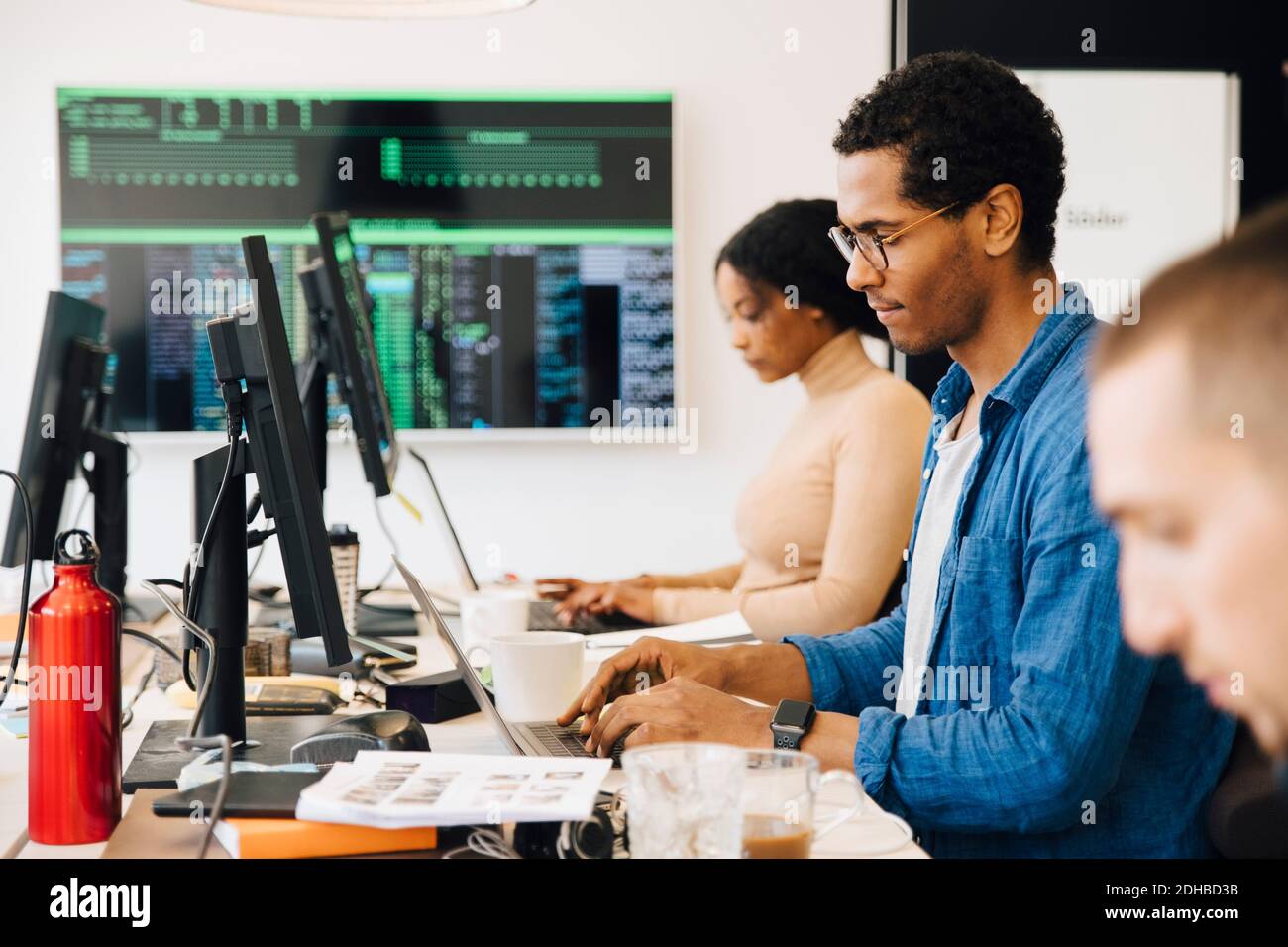 Side view of male with female computer hackers using laptops on desk ...