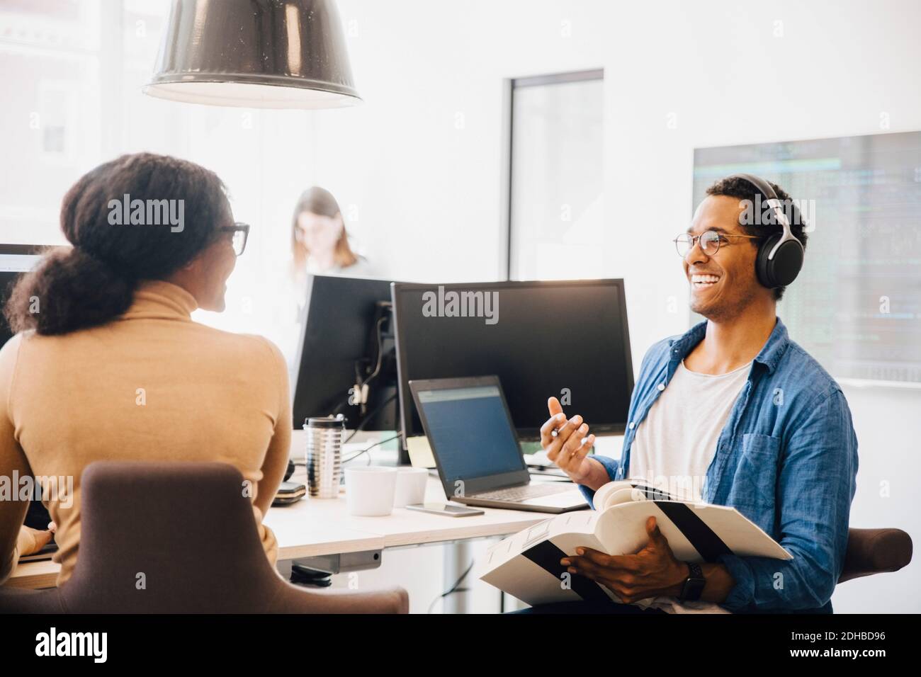 Cheerful male computer hacker talking with female coworker while ...