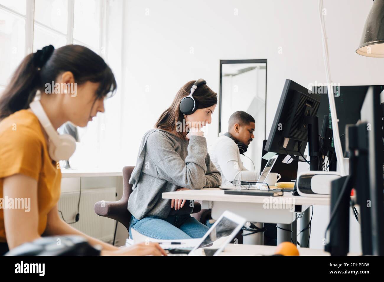 Side view of focused programmers using laptops on desk while sitting in ...