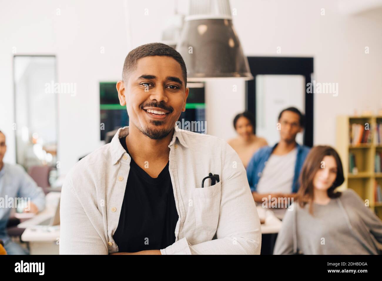 Portrait of smiling computer programmer standing with colleagues in ...