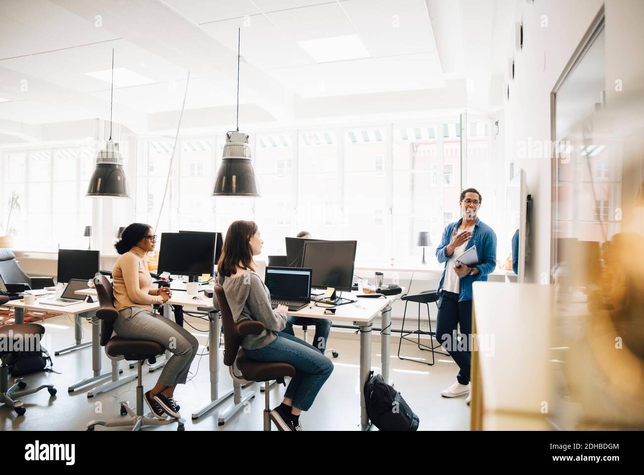 Computer programmer explaining code to colleagues during meeting in ...