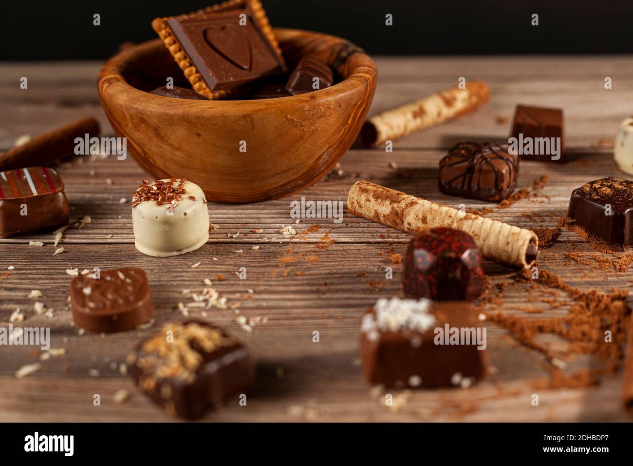 A bowl of assorted chocolates and chocolate biscuits on wooden ...