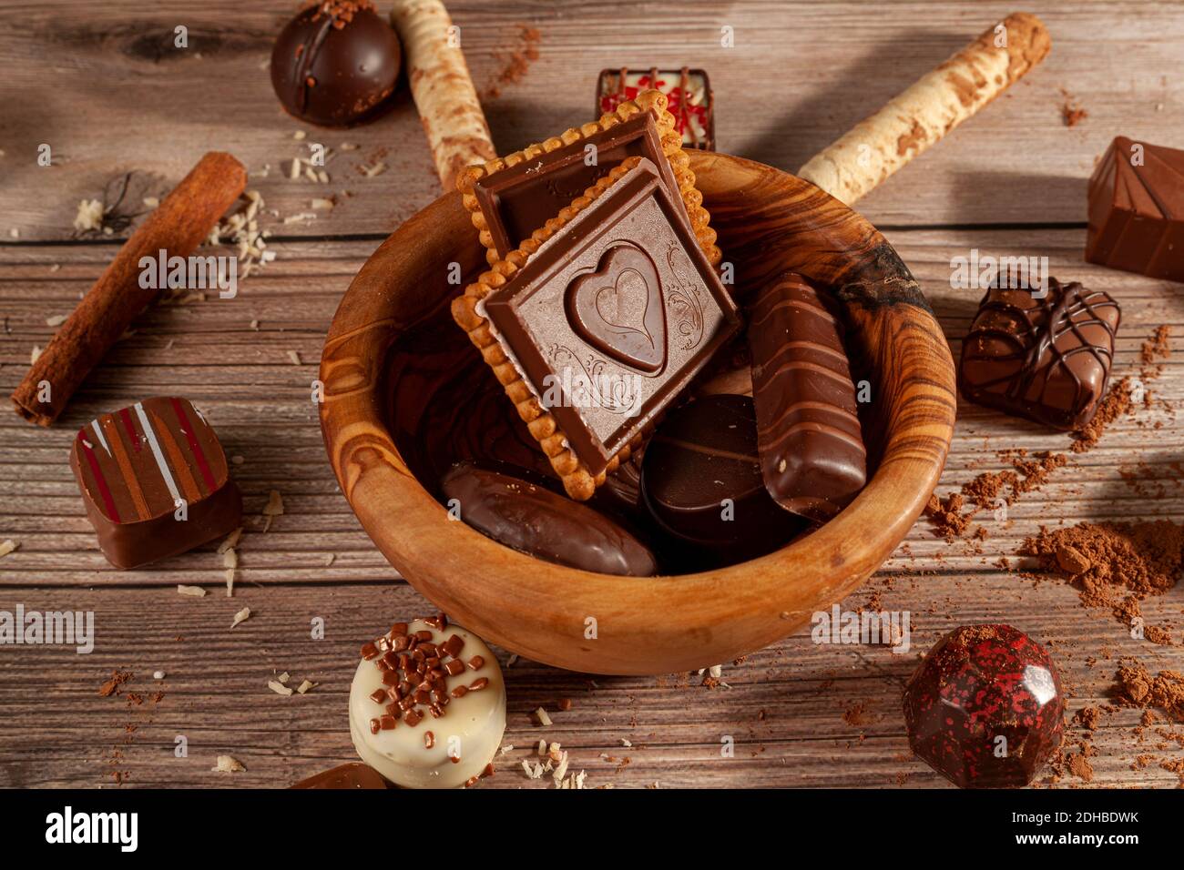 A bowl of assorted chocolates and chocolate biscuits on wooden ...
