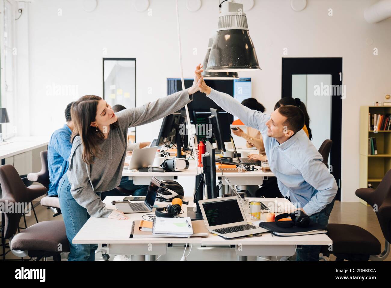 Happy male and female computer programmers doing high-five over ...